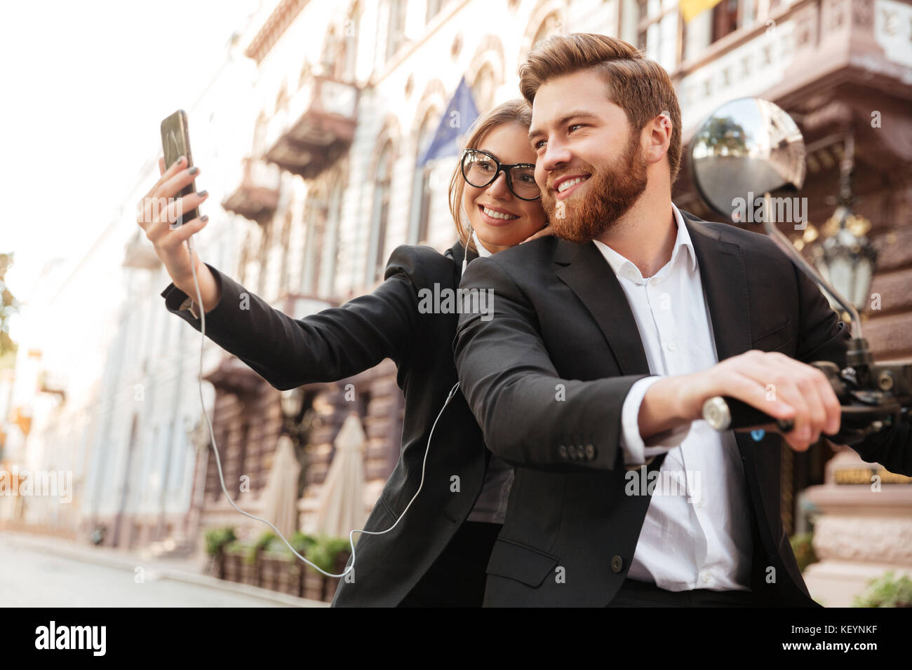 Smiling stylish couple satting on modern motorbike outdoors and making ...