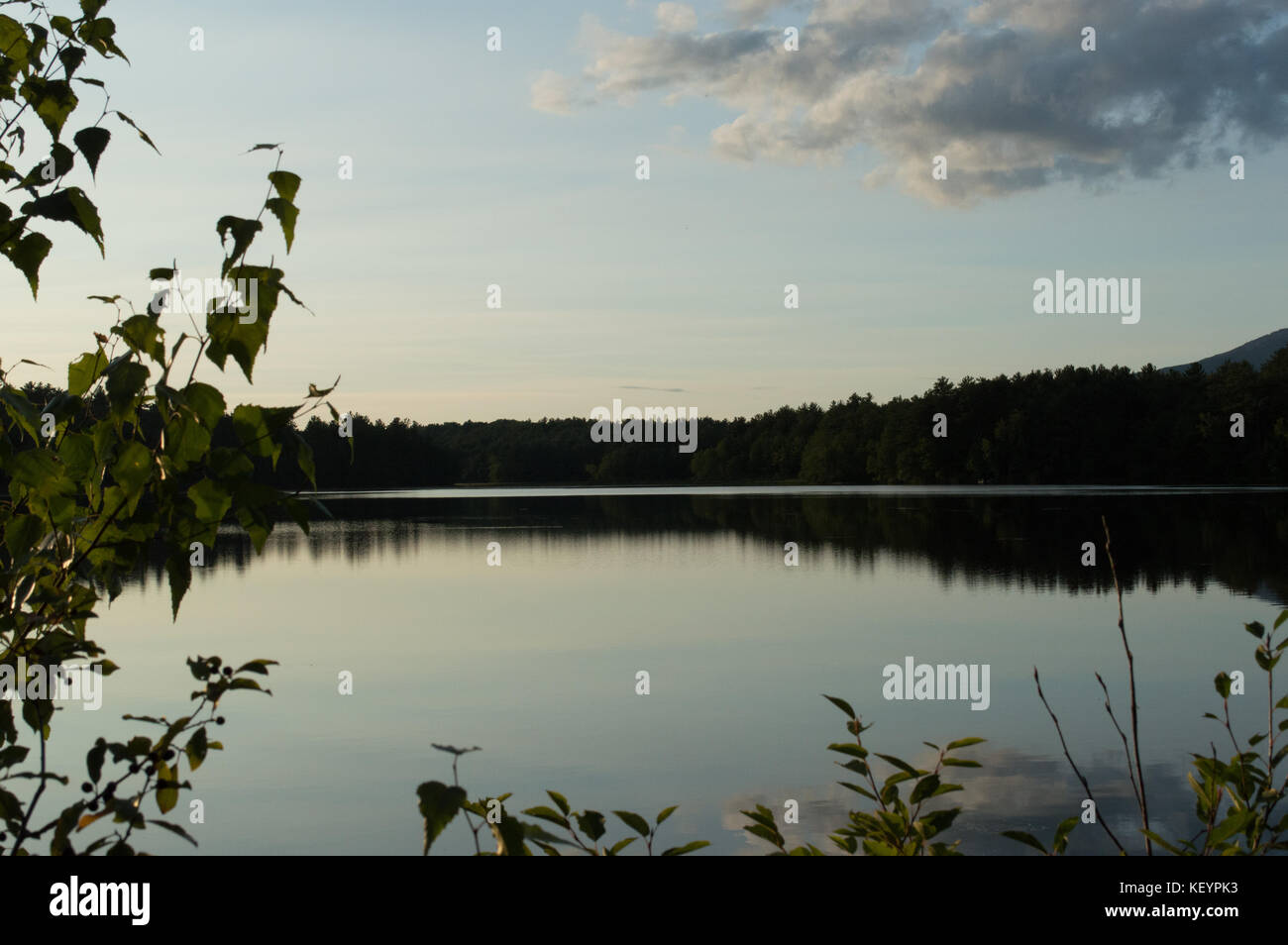 Gorgeous New Hampshire lake reflects the sky on a fall afternoon during ...