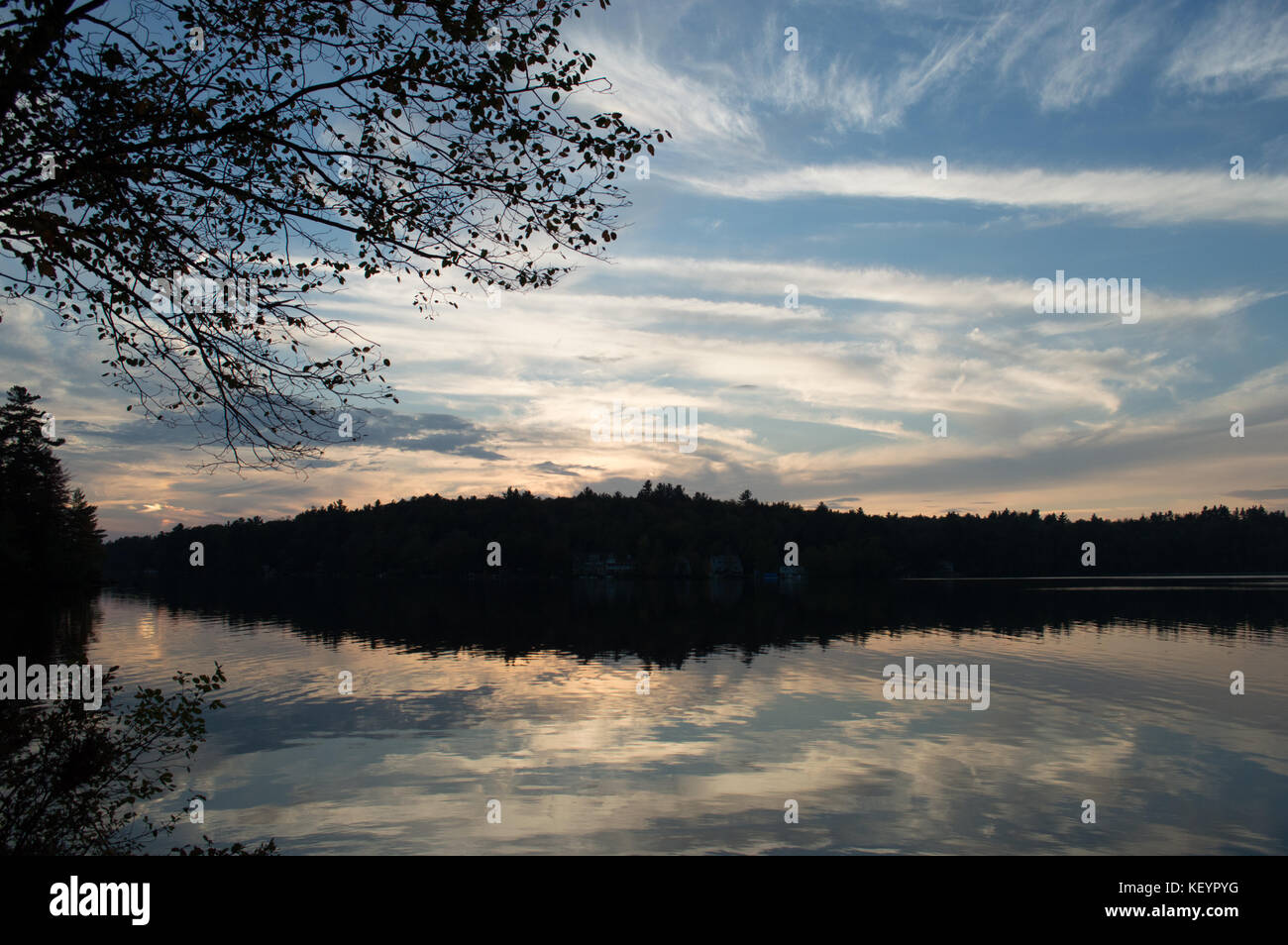 Gorgeous New Hampshire lake reflects the sky on a fall afternoon during ...