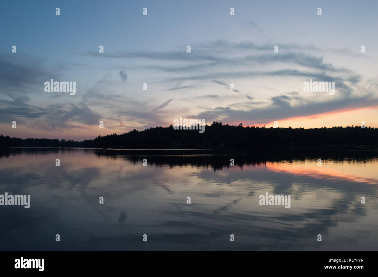 Gorgeous New Hampshire lake reflects the sky on a fall afternoon during ...