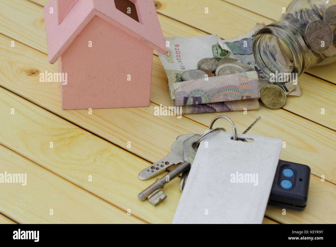 Miniature house,money spilling out from the glass jar,set of keys with ...