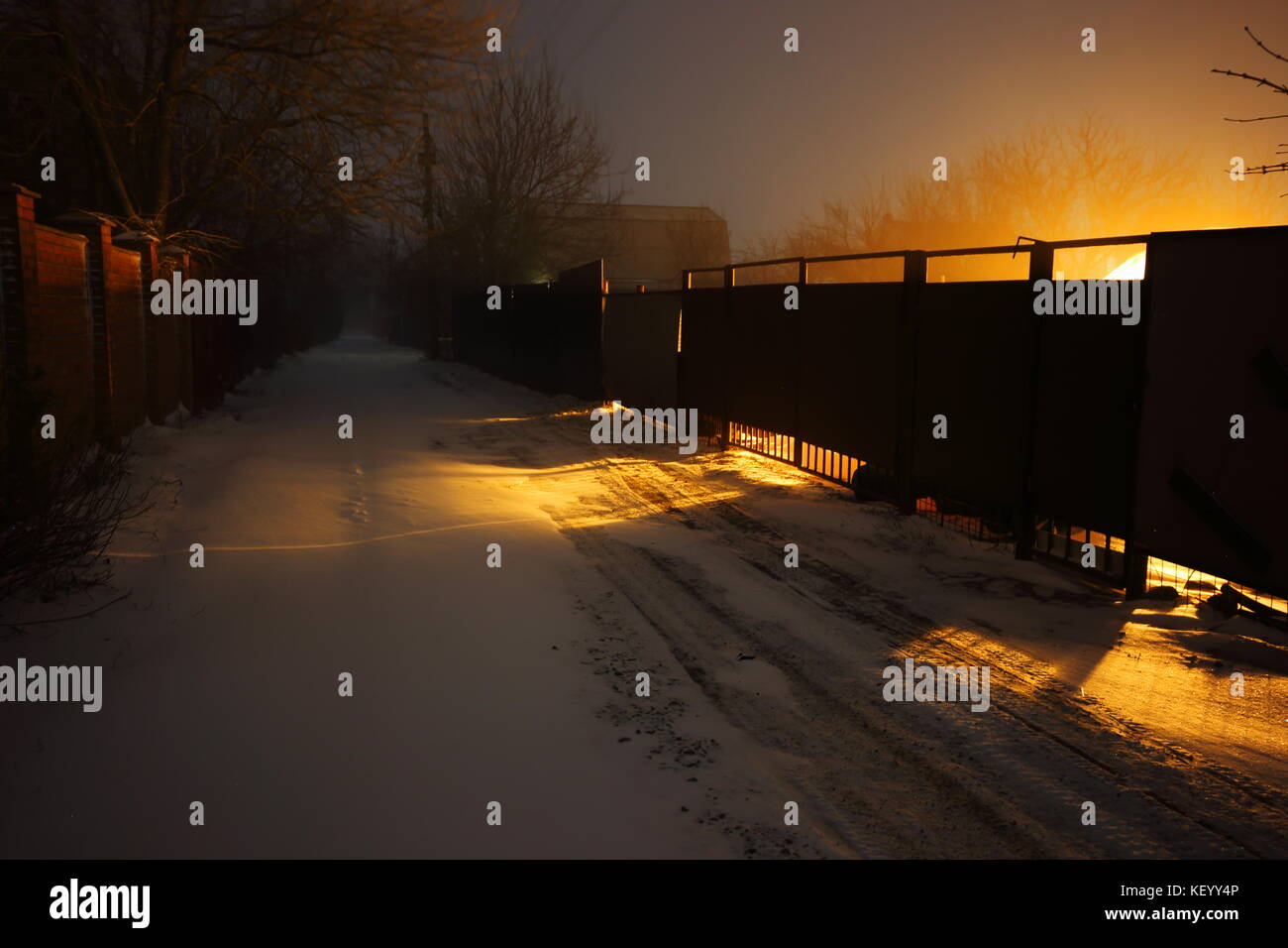Snow covered suburban road lit by yellow lights at night time Stock ...