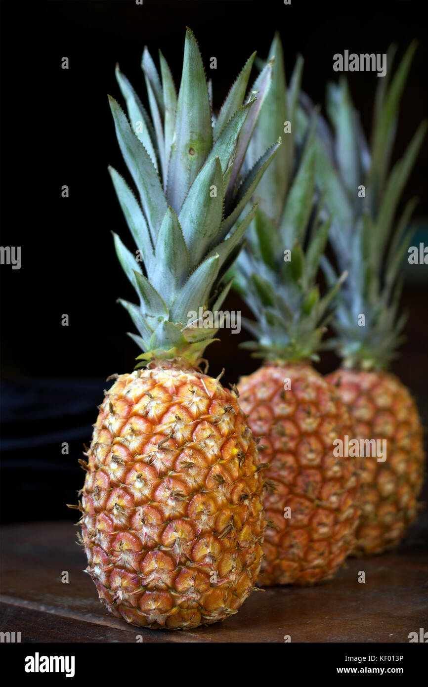 Close-up on three pineapples in a row on brown table and black ...