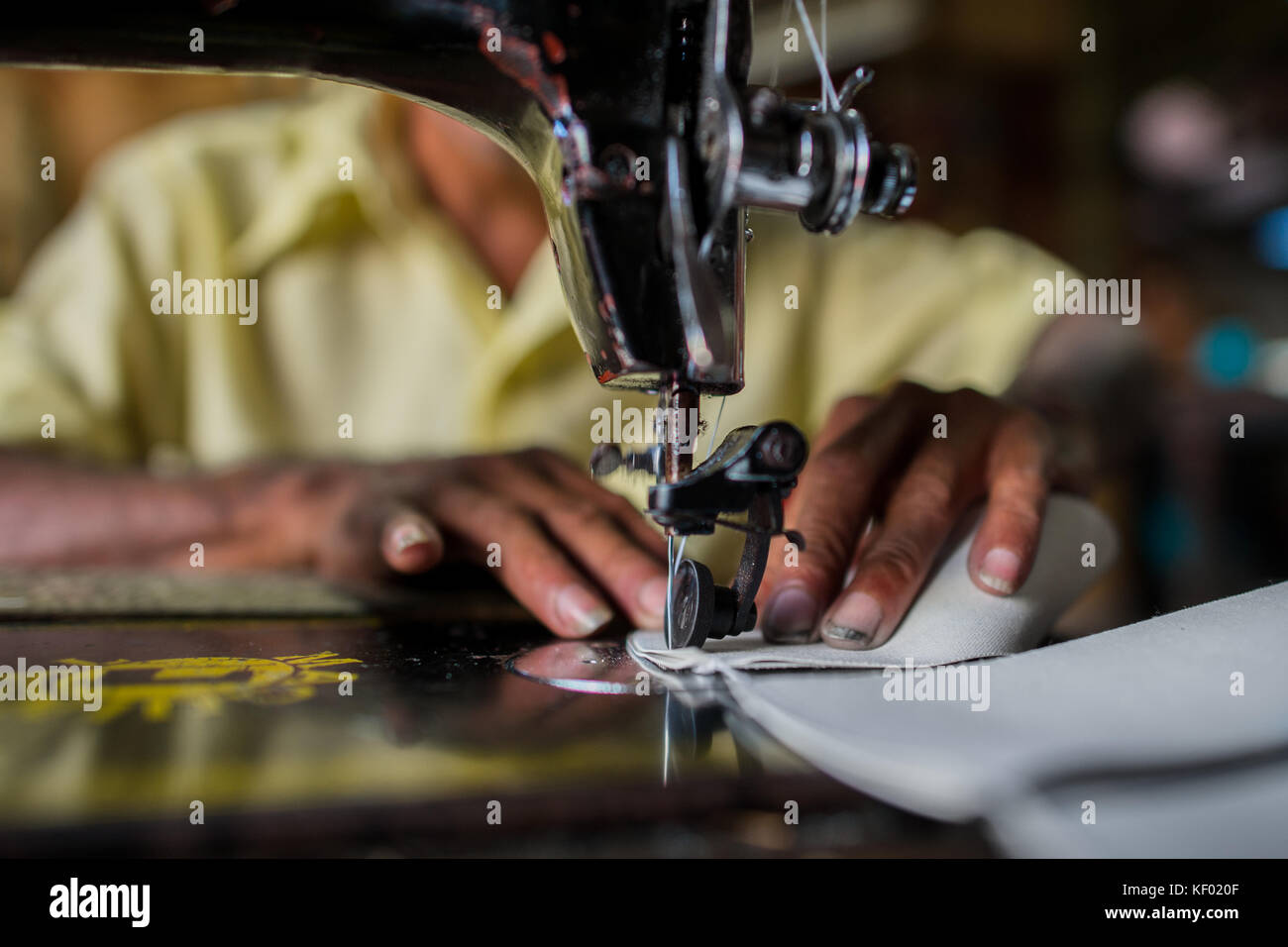 A Salvadoran shoemaker works on a sewing machine, stitching shoe uppers ...