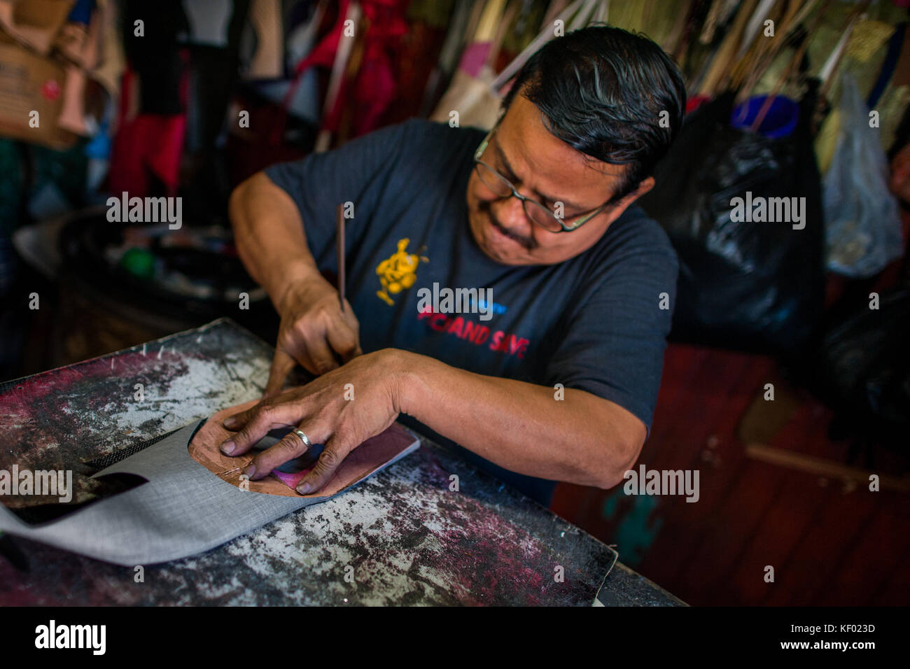 A Salvadoran shoemaker cuts a shoe upper from a fiber sheet on the ...