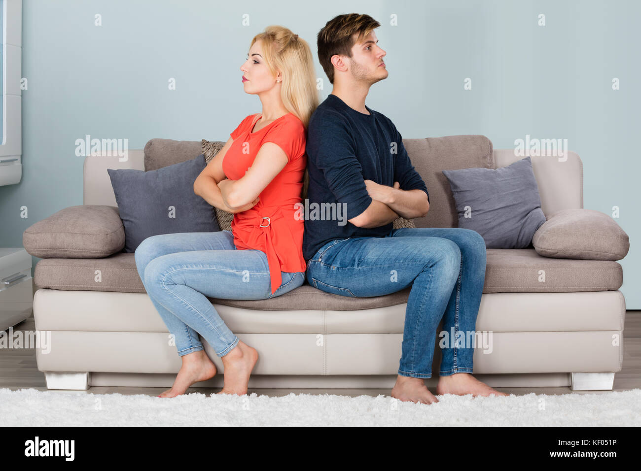 Young Sad Couple In Fight With Arms Crossed Sitting On Sofa After
