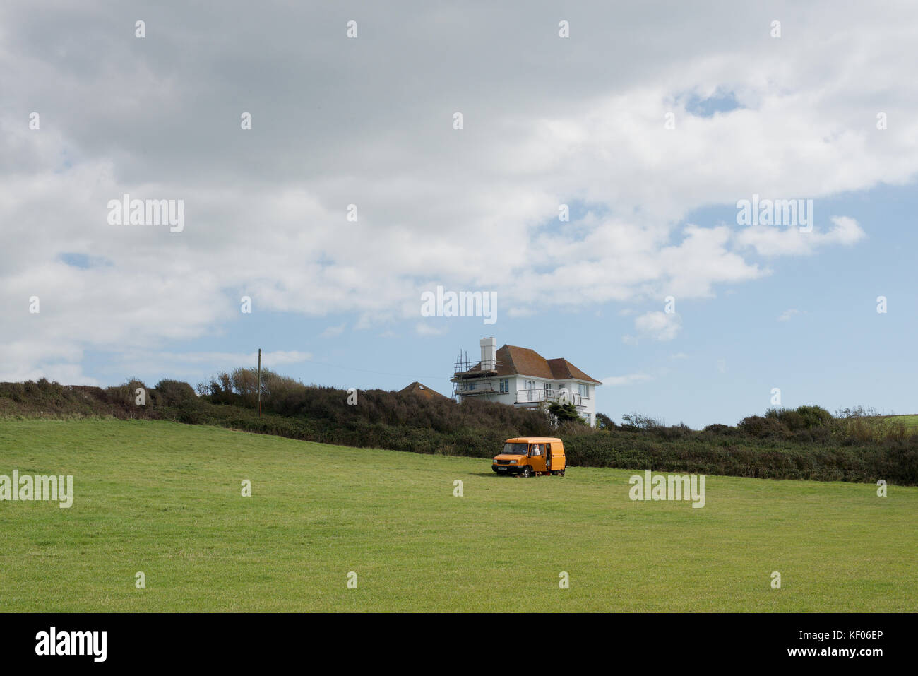 Orange van in the middle of a big field near a house Stock Photo - Alamy