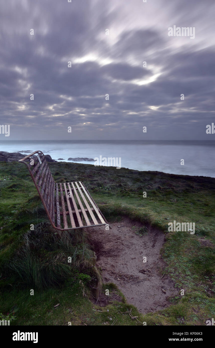 An iron and wooden park bench on top of the cliffs looking over the sea ...