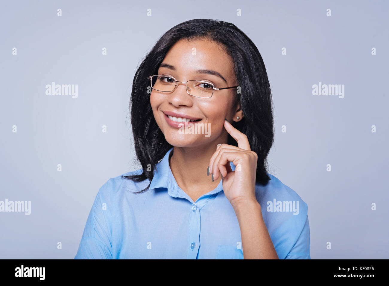 Pleasant woman in glasses touching her cheek with finger Stock Photo ...