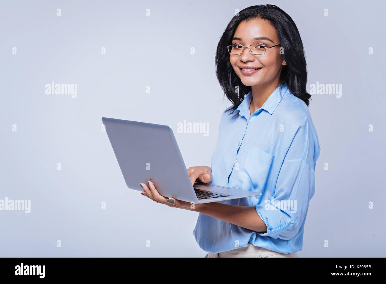 Beautiful woman posing with laptop against blue background Stock Photo ...