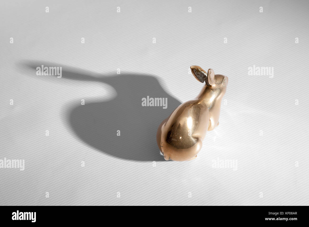Brass Ornament of a sitting rabbit casting a shadow Stock Photo - Alamy