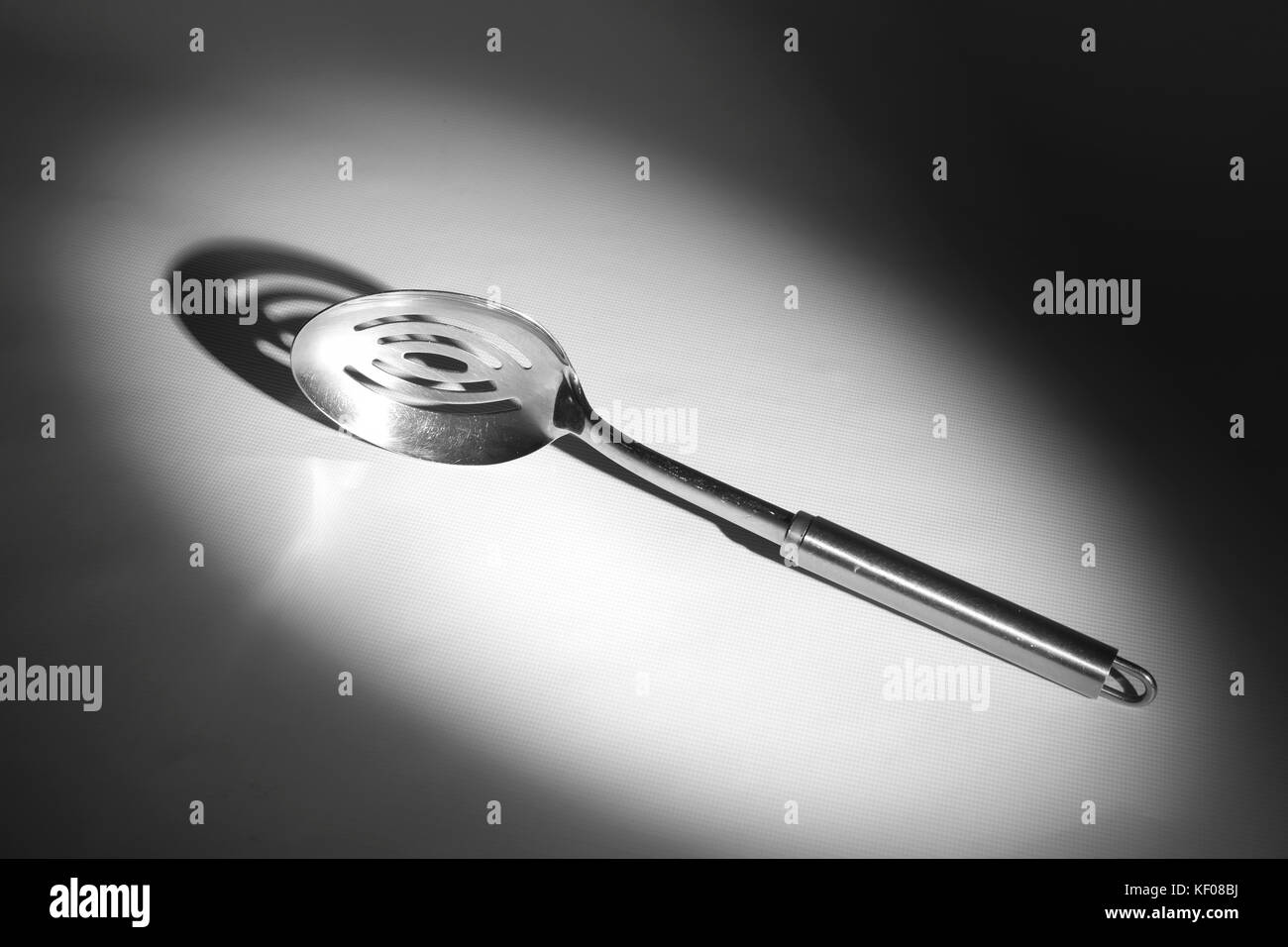 Kitchine straning spoon casting a shadow Stock Photo - Alamy