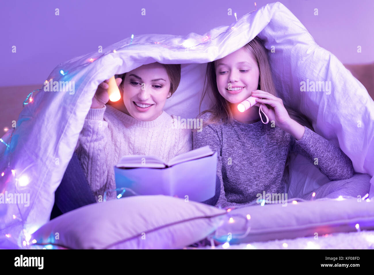Devoted mom and daughter reading under the blanket Stock Photo - Alamy