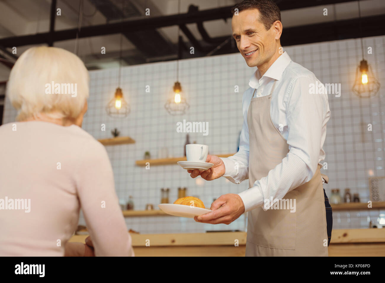 Joyful positive waiter serving breakfast Stock Photo - Alamy