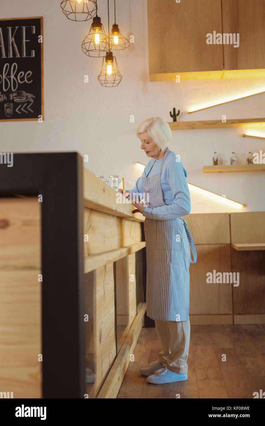 Pleasant senior woman standing at the counter Stock Photo - Alamy