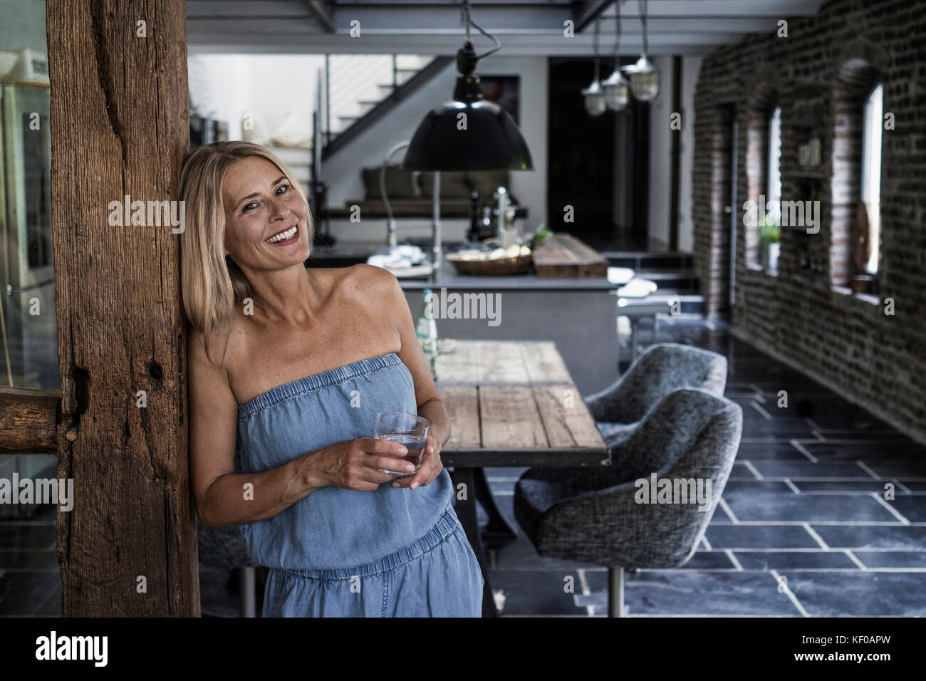 Woman standing in her comfortable country house, smiling Stock Photo ...