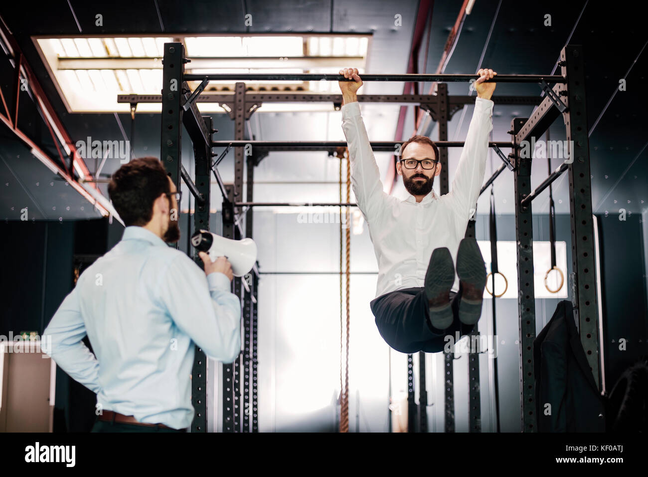 Manager with megaphone giving businessman hanging on bar orders Stock ...