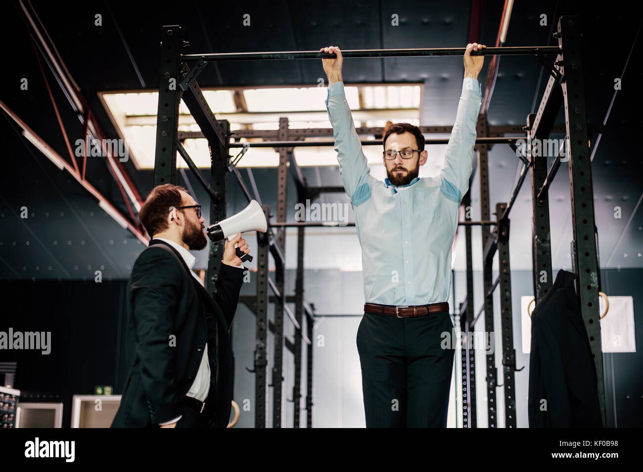 Manager with megaphone giving businessman hanging on bar orders Stock ...