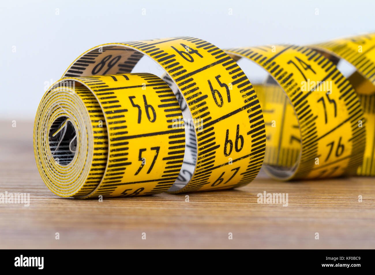 Close up detailed view of yellow tape measure on wooden background ...