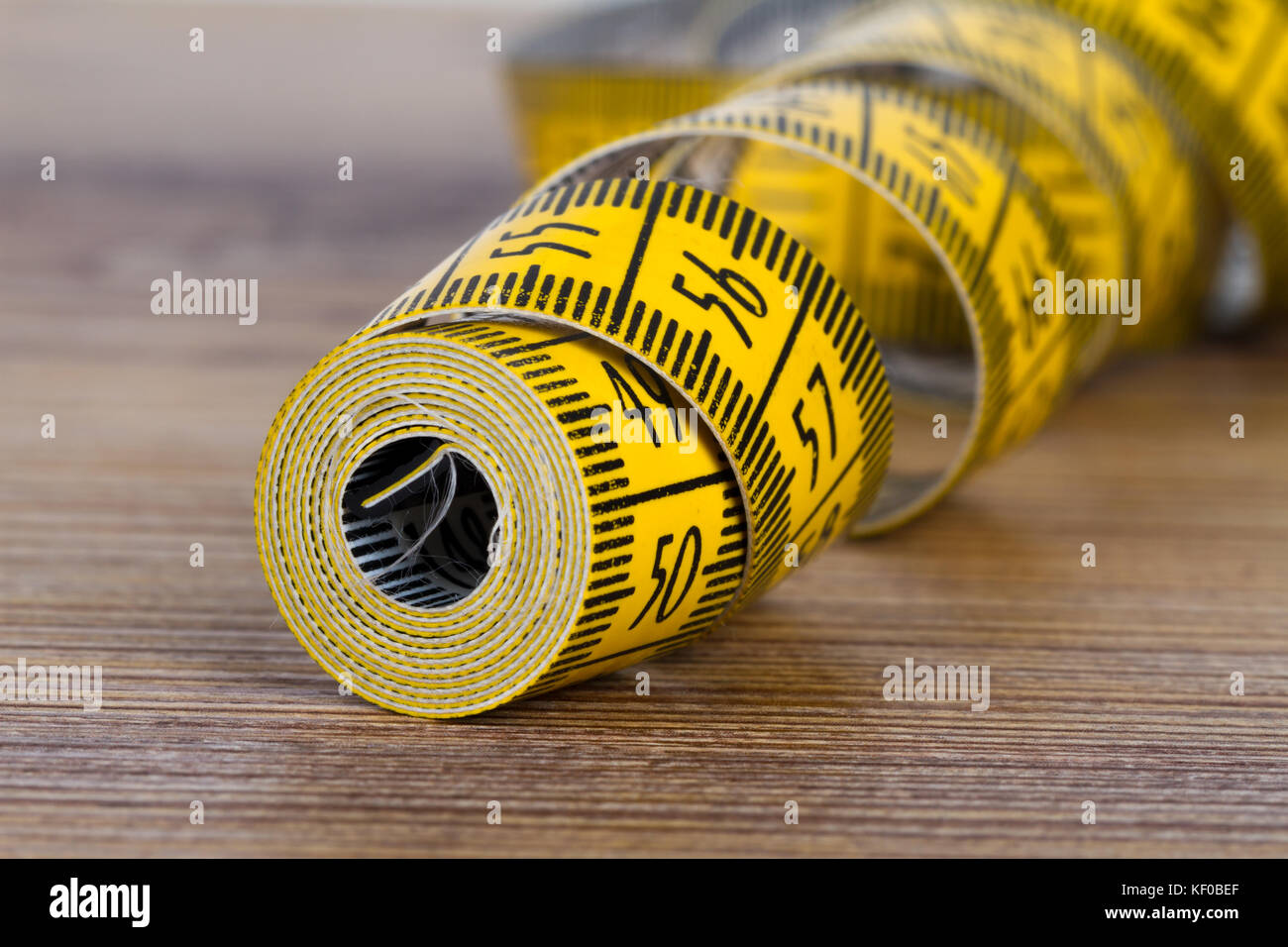 Close up detailed view of yellow tape measure on wooden background ...