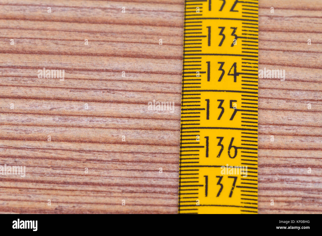 Close up detailed view of yellow tape measure on wooden background ...