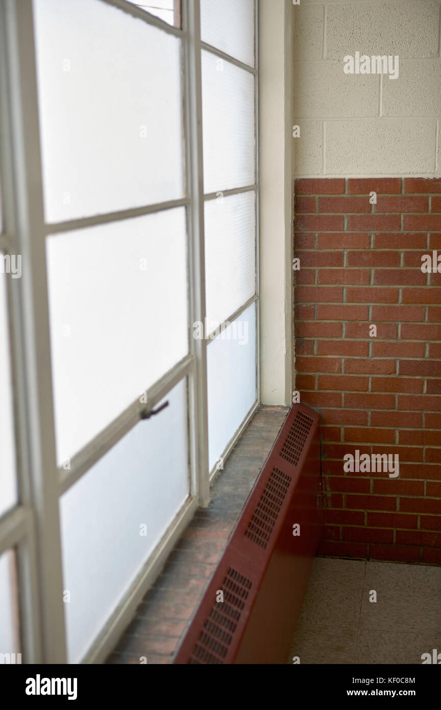 Old radiator under a metal framed window in a building with half face ...
