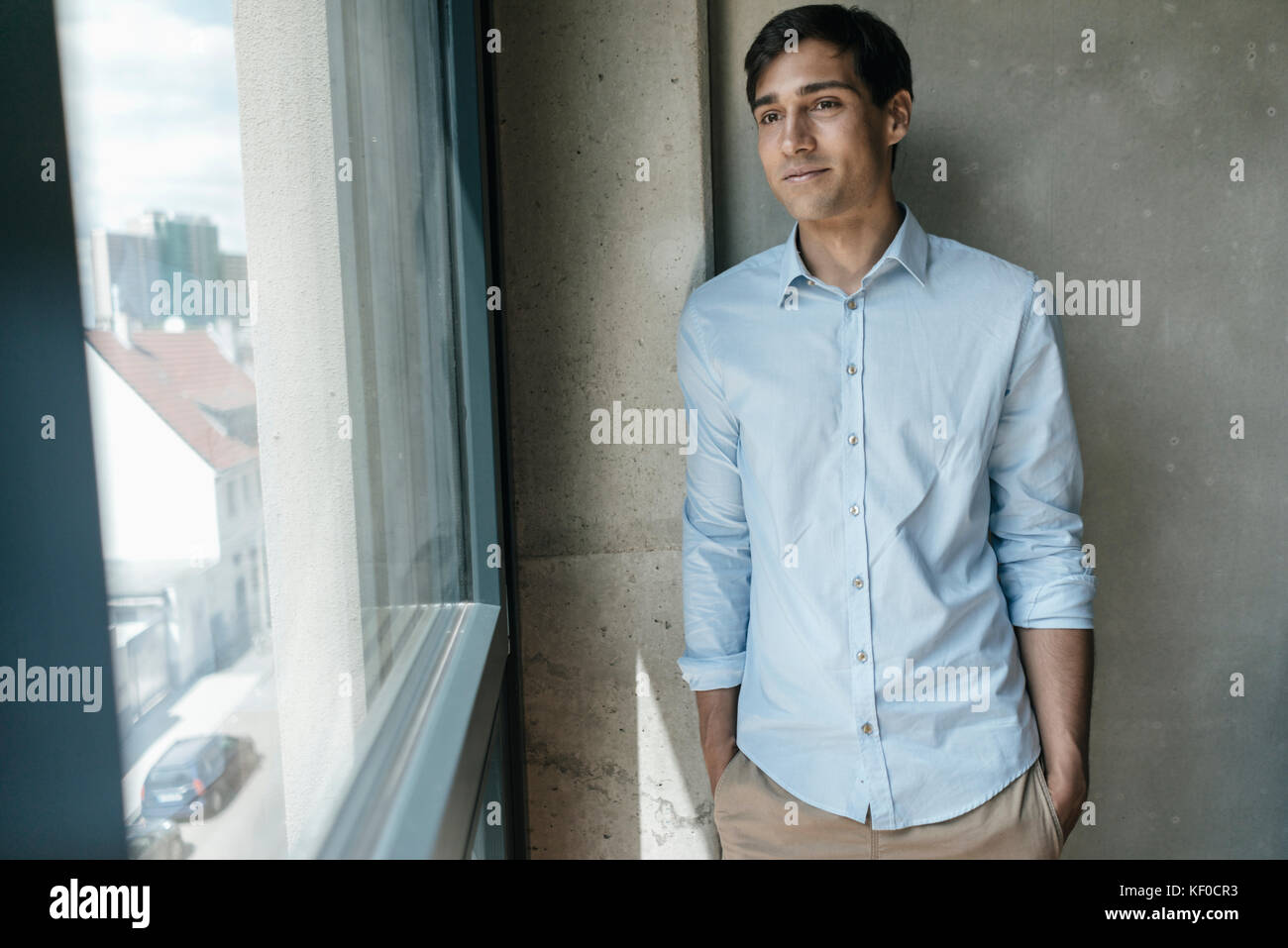 Smiling young man looking out of window Stock Photo - Alamy