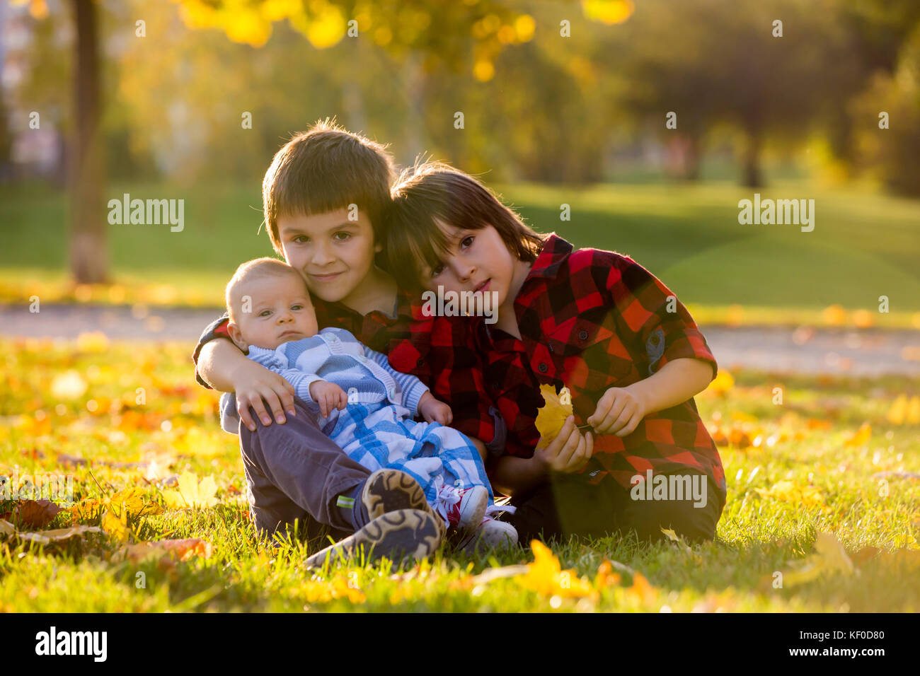Three happy children, boy brothers, having fun in the park, autumn time ...