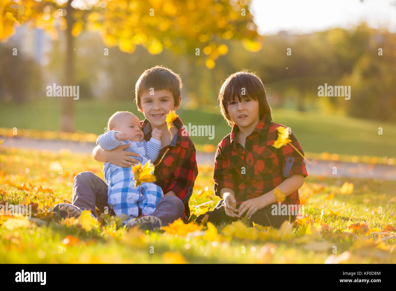 Three happy children, boy brothers, having fun in the park, autumn time ...