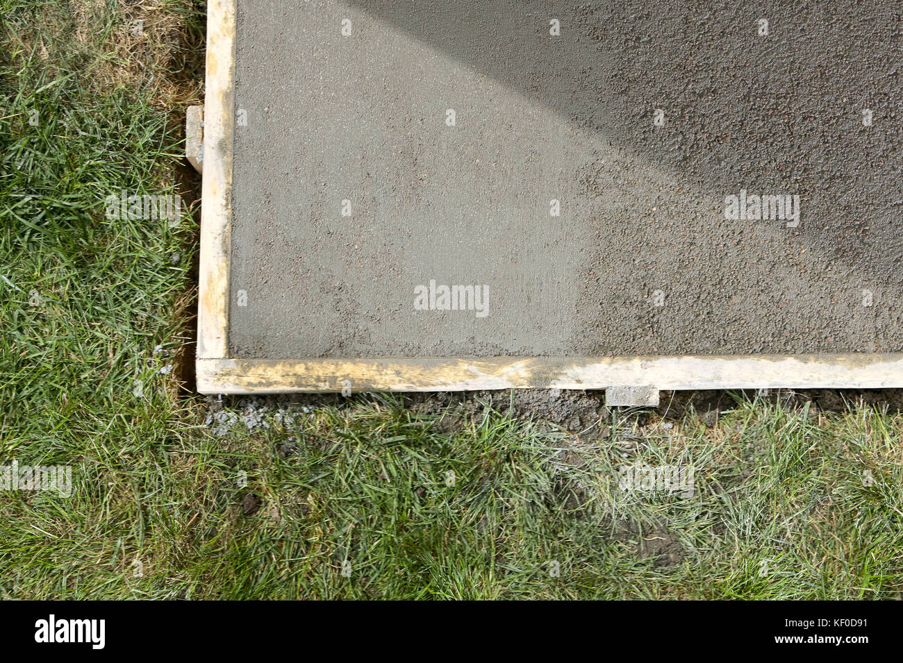 A close up crop of timber form work and half finished, wet cement in a ...