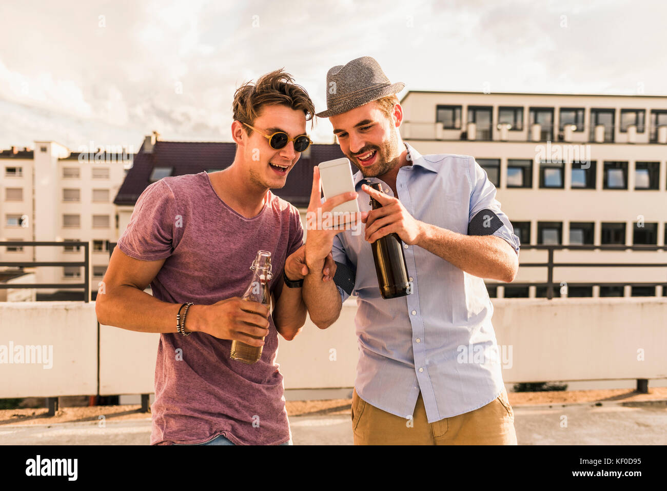 Two friends with beer bottles and cell phone on rooftop Stock Photo - Alamy
