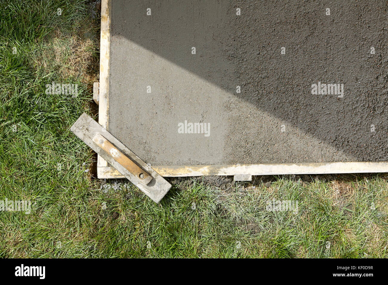 A close up of a wet cement slab, form work and wooden screed in a DIY ...