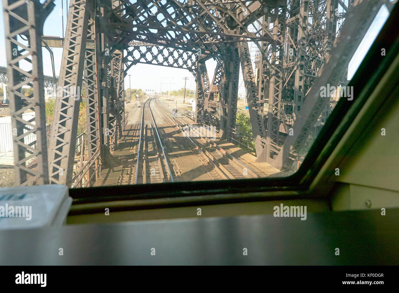 View of a bridge with train tracks over a river through a train window ...