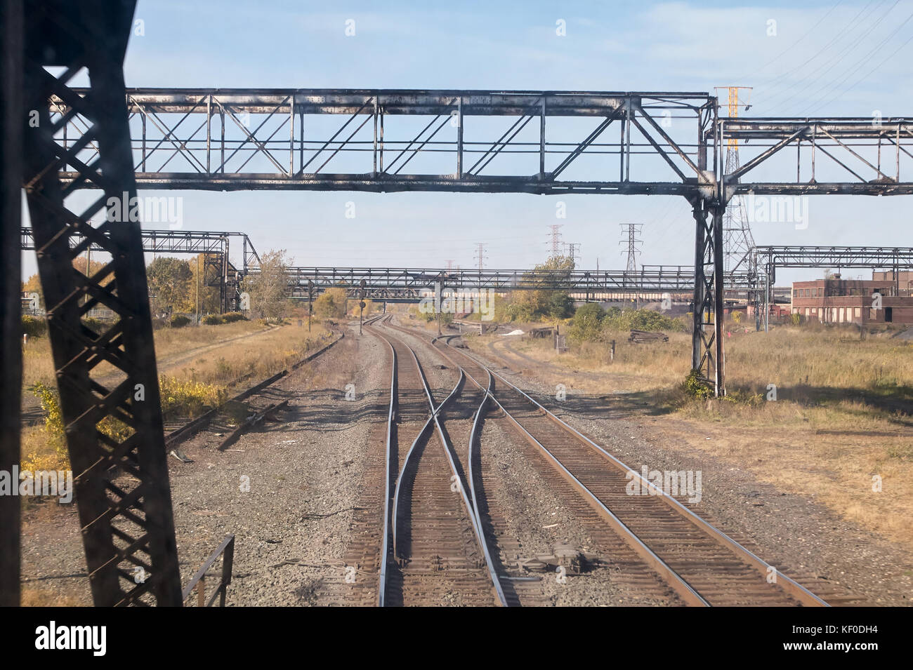 Front view of a brightly sunlit train yard and tracks with foliage from ...