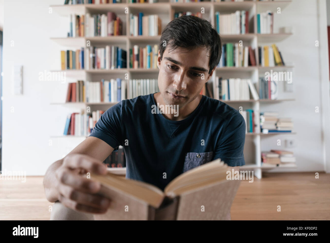 Young man reading book at home Stock Photo - Alamy