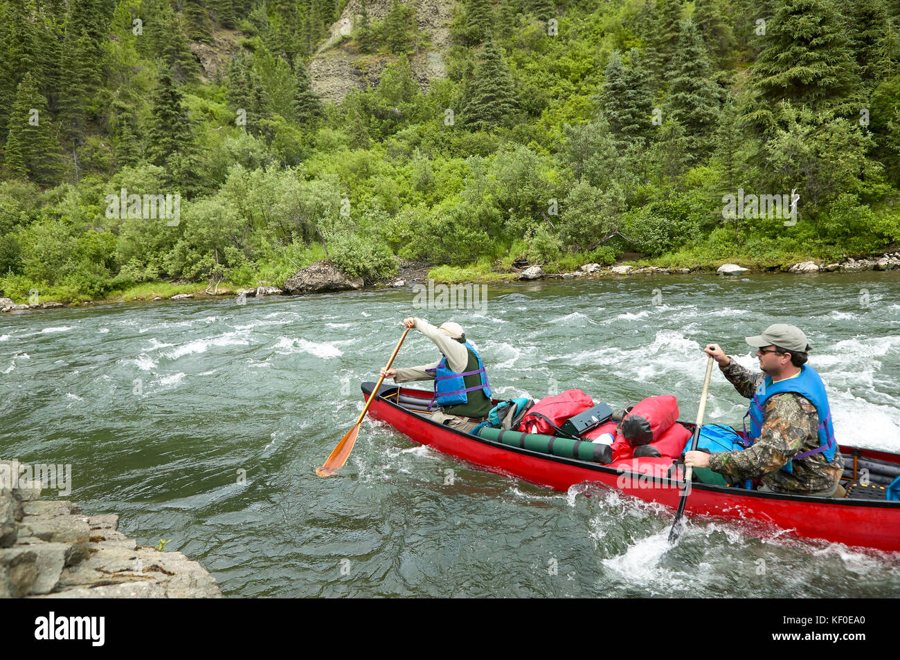 Two men navigate a canoe through rushing, turbulent rapids during an ...
