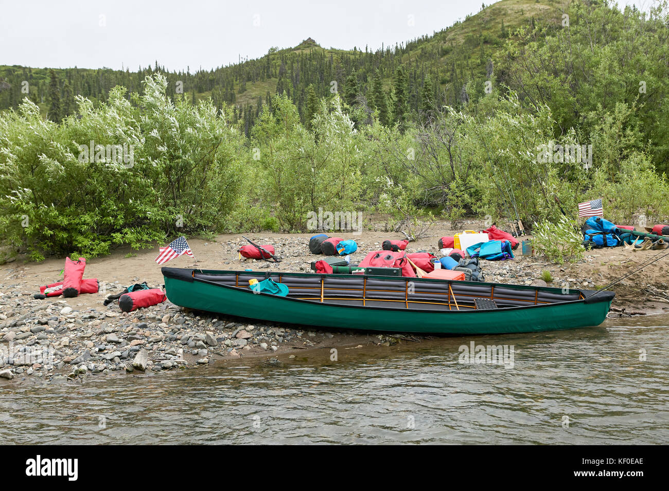 A beached canoe on an Alaskan river with wet gear and equipment drying ...