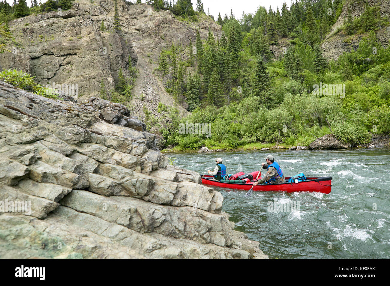 Two canoeists navigate rocks and shallow water during an adventure on a ...
