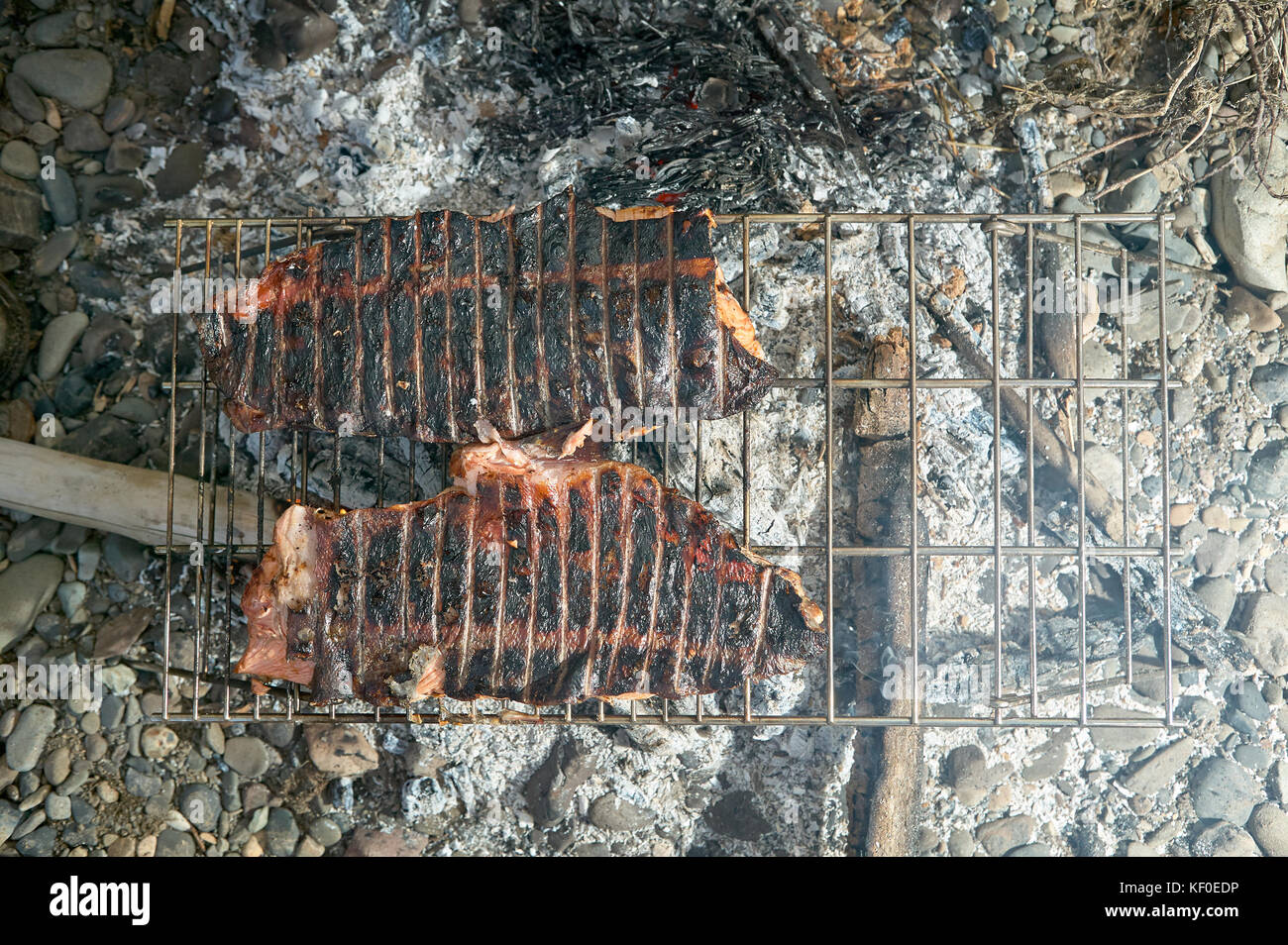 Fish fillets grilling and charring on hot, smokey open fire coals Stock ...