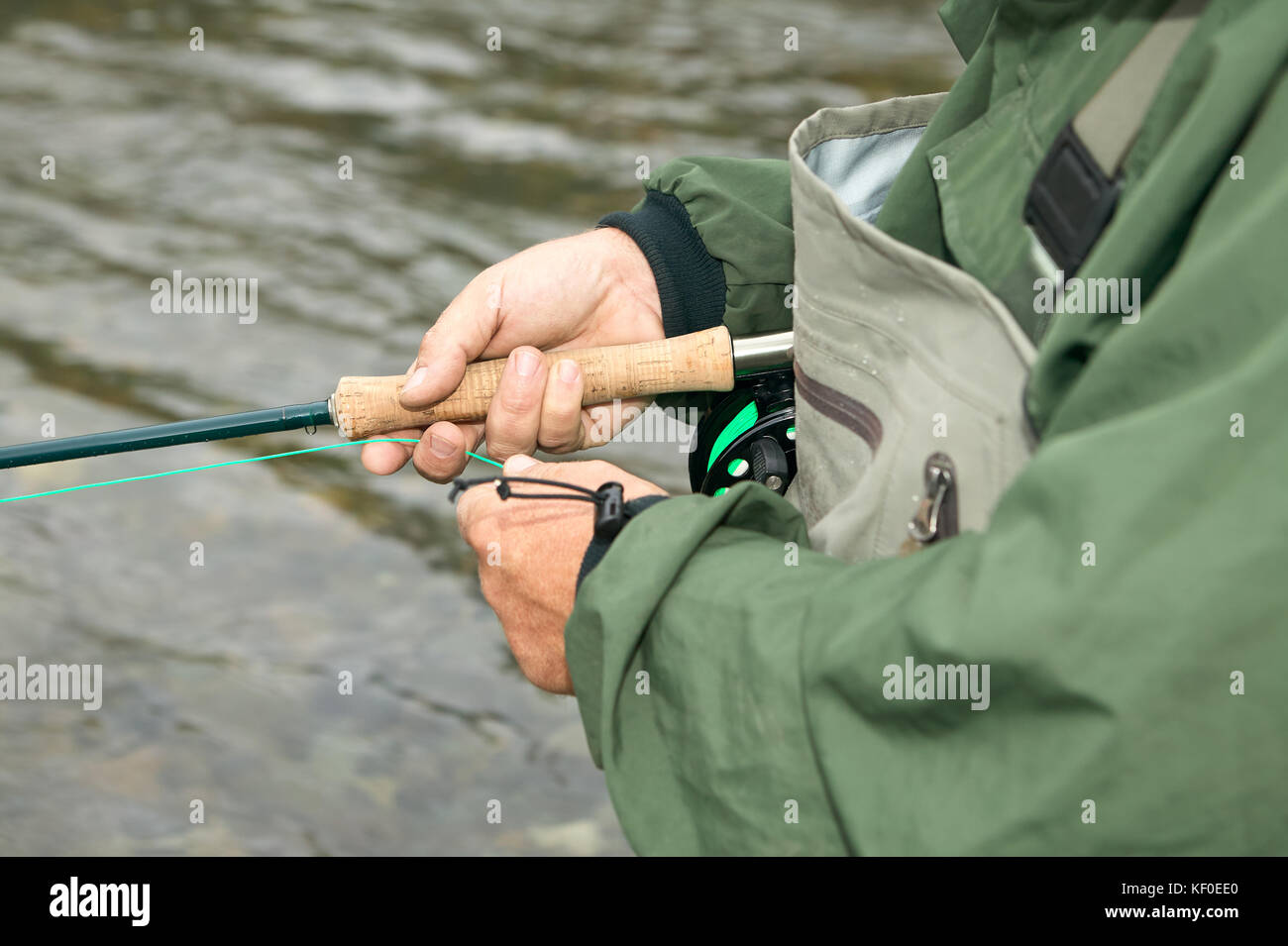 Close up image of a male fisherman hands, reel and line as he fishes in ...