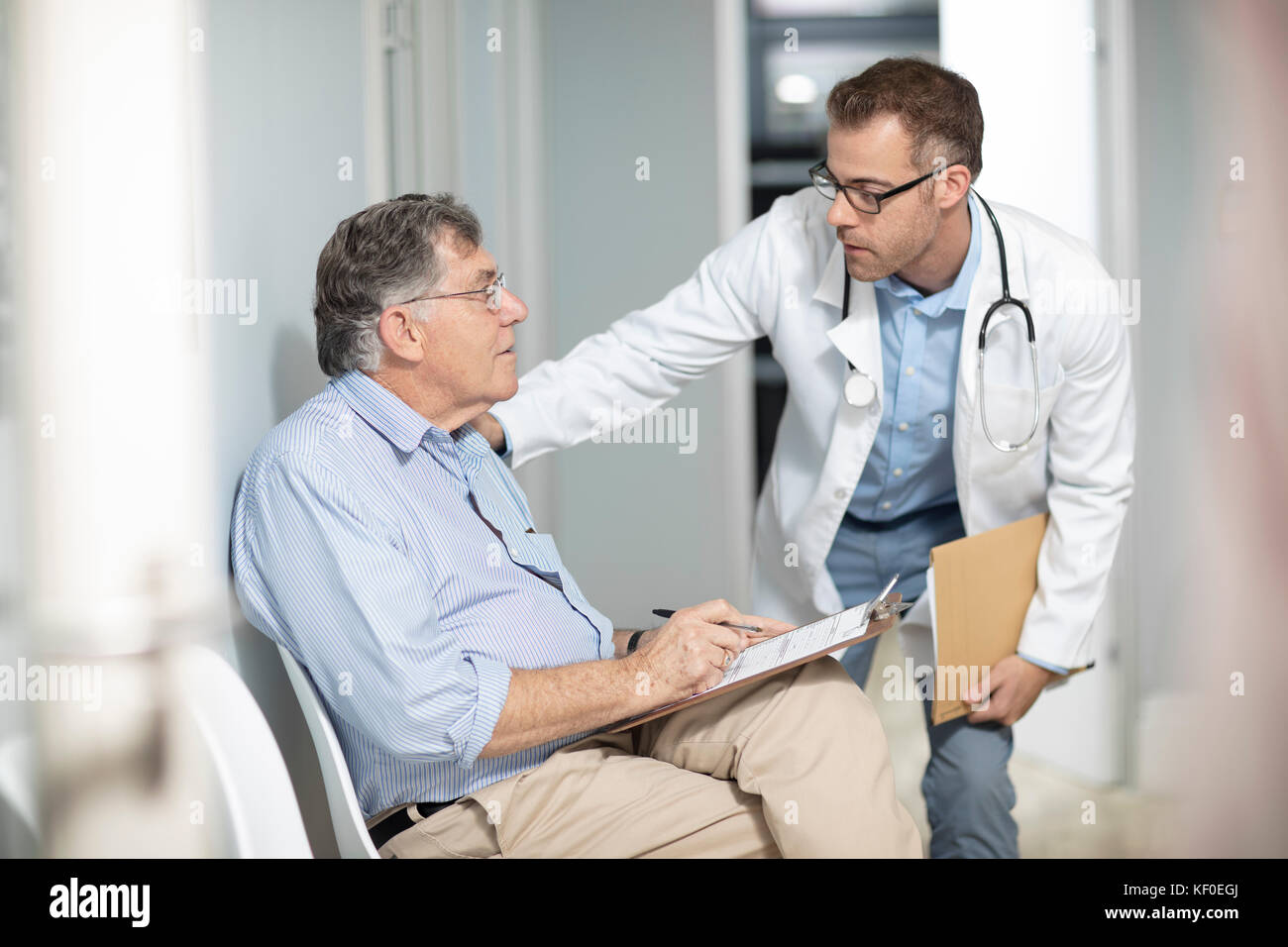 Doctor talking to patient with file in medical practice Stock Photo - Alamy