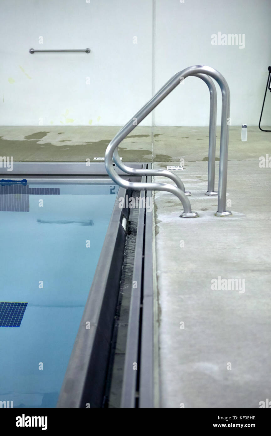 Curved metal handrails on swimming pool steps viewed along the edge of ...