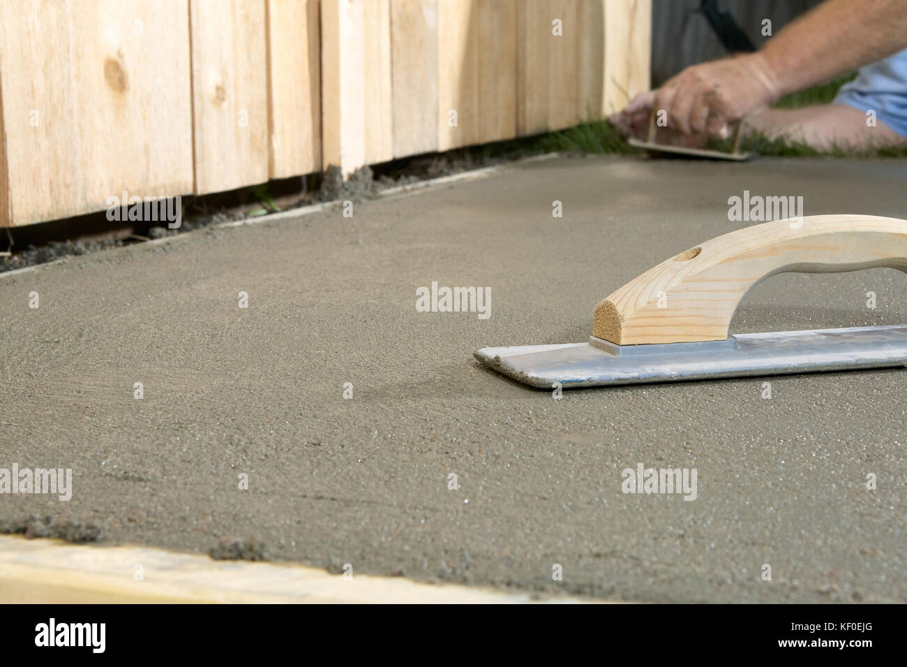 A close up of a concrete screed on a wet cement slab as a person uses ...
