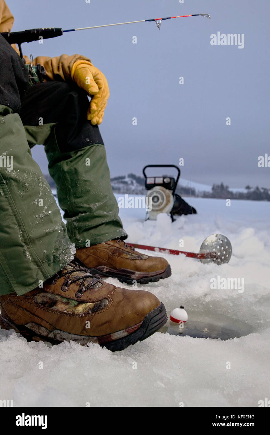 A close up of an ice fisherman float fishing in an ice hole and ...