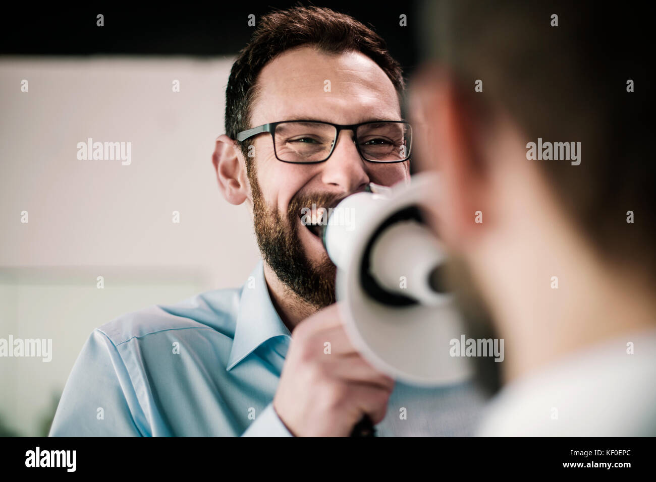 Manager with megaphone giving businessman orders Stock Photo - Alamy