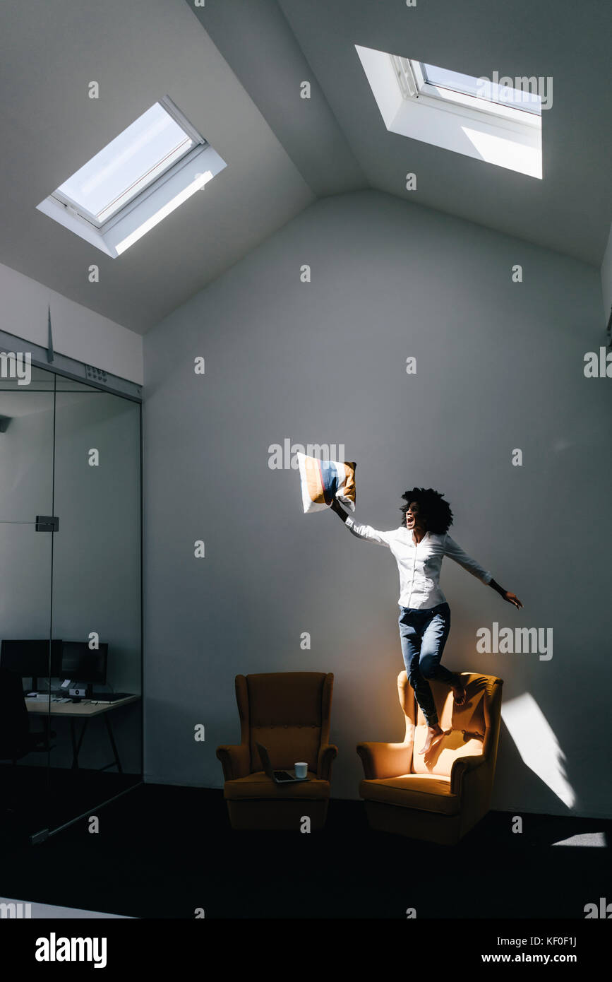 Cheerful woman jumping on chair hi-res stock photography and images - Alamy