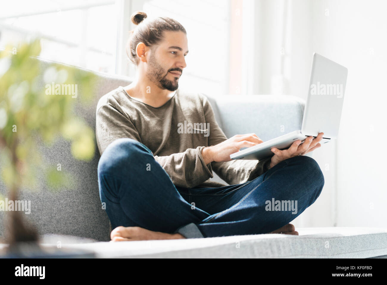 Portrait of man sitting on the couch using laptop Stock Photo - Alamy