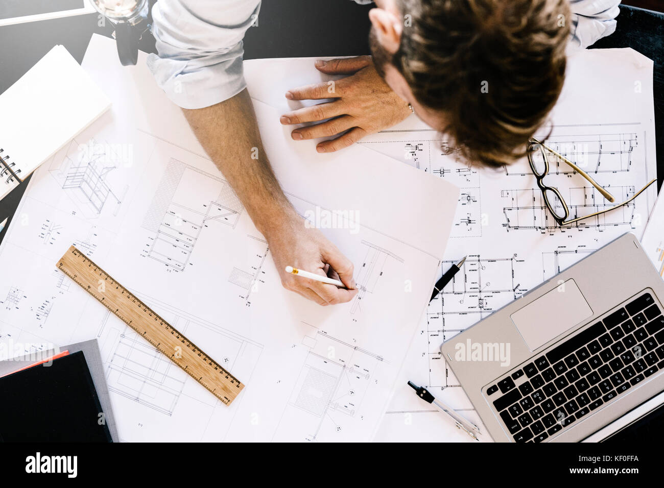 Man working on construction plan at desk, top view Stock Photo - Alamy