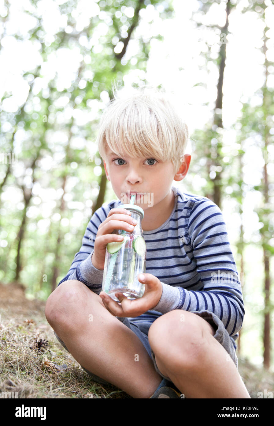 Boy drinking from glass of infused water in forest Stock Photo - Alamy