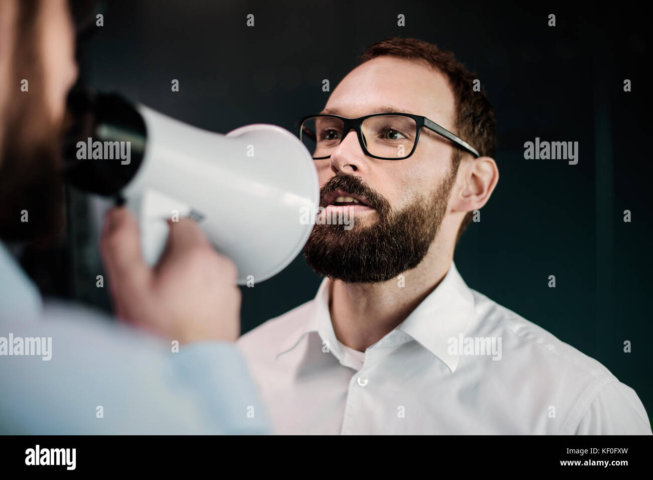 Manager with megaphone giving businessman orders Stock Photo - Alamy